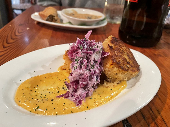 A golden crab cake perched on a pool of sunshine-yellow sauce with purple slaw&mdash;it's like edible modern art with Southern sensibilities.
