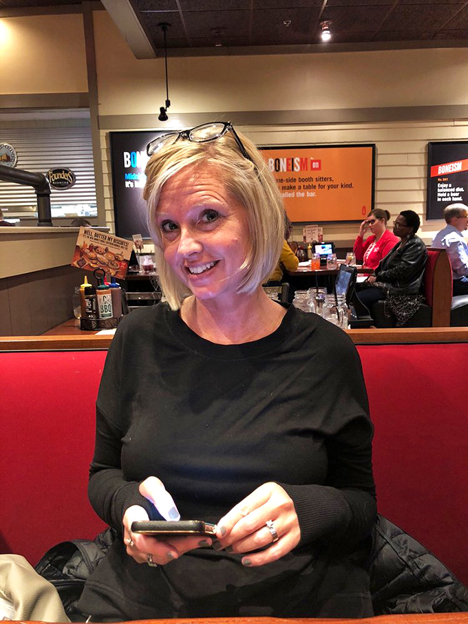 The dining room at Smokey Bones offers comfortable red booths where serious barbecue business happens in a casual atmosphere.