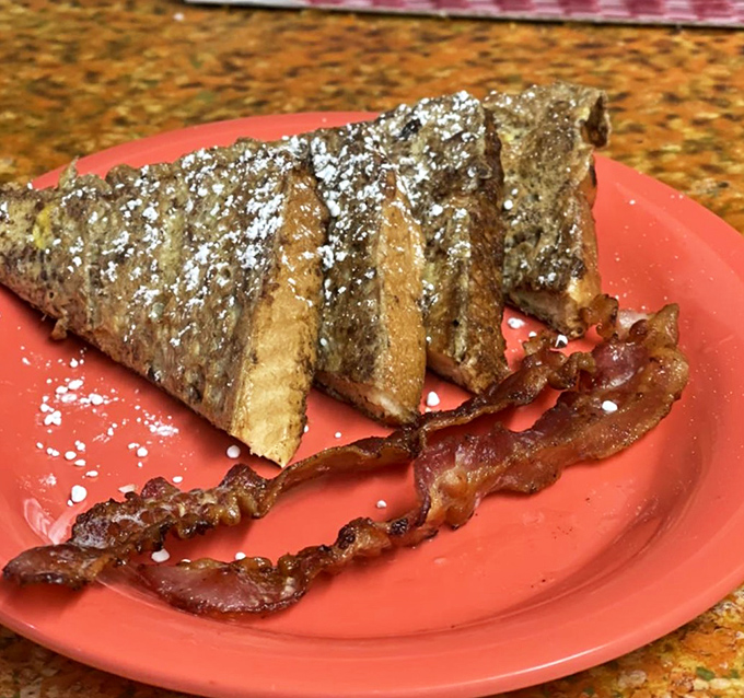French toast dusted with powdered sugar like the first snow of winter, with bacon strips standing guard to ensure the perfect sweet-savory balance.