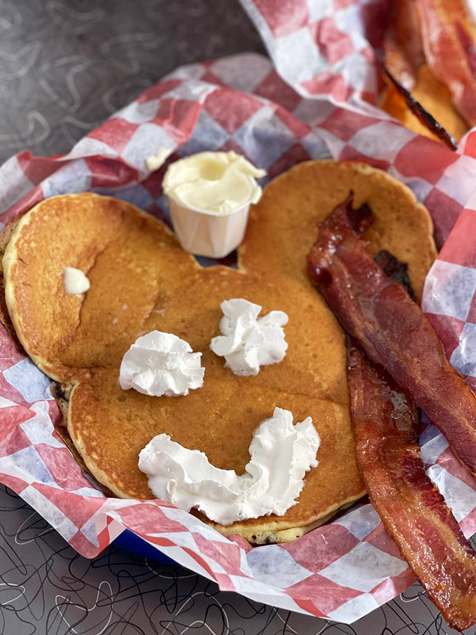 Mickey-shaped pancakes prove that food tastes better when it's smiling at you. The bacon's just there to keep things from getting too cute.