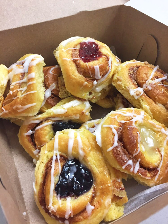 A box of mini Danish pastries showcasing jewel-toned fruit centers &ndash; the perfect peace offering for arriving late to any family gathering.