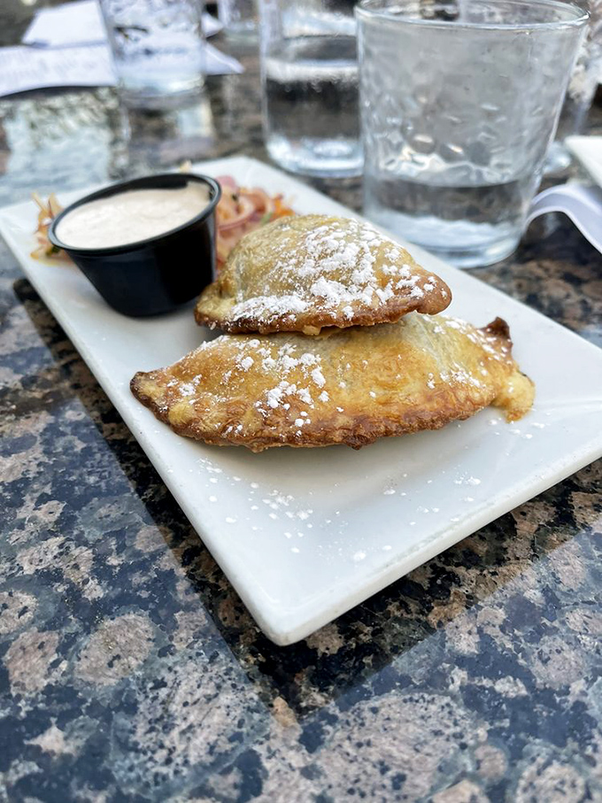 These golden-brown empanadas dusted with powdered sugar aren't just appetizers; they're little pockets of joy that make waiting for your entr&eacute;e a pleasure, not a chore.
