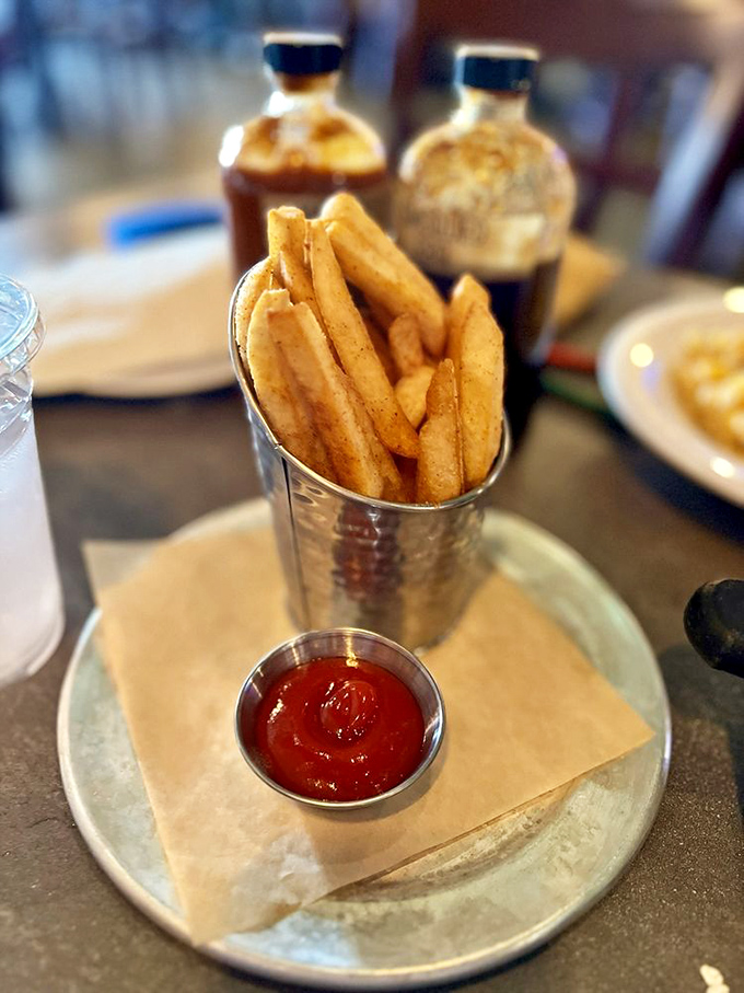 Seasoned fries standing at attention in their metal cup, ready to dive into that sauce. They're the unsung heroes of any BBQ plate.