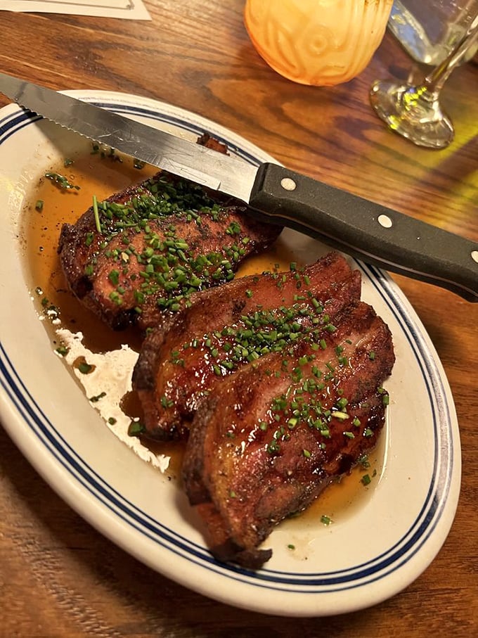 Slab bacon that's been transformed from breakfast sidekick to main character. The glistening chive garnish isn't just pretty&mdash;it's necessary balance.