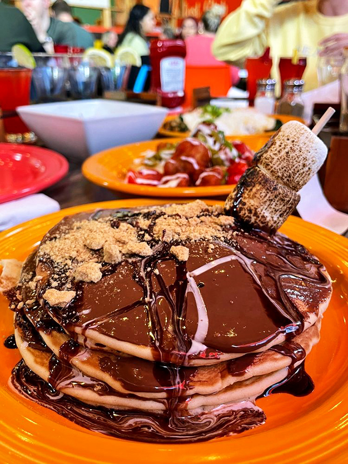 Chocolate cascading down pancake cliffs with a toasted marshmallow perched on top like a sugary mountaineer surveying its delicious domain.