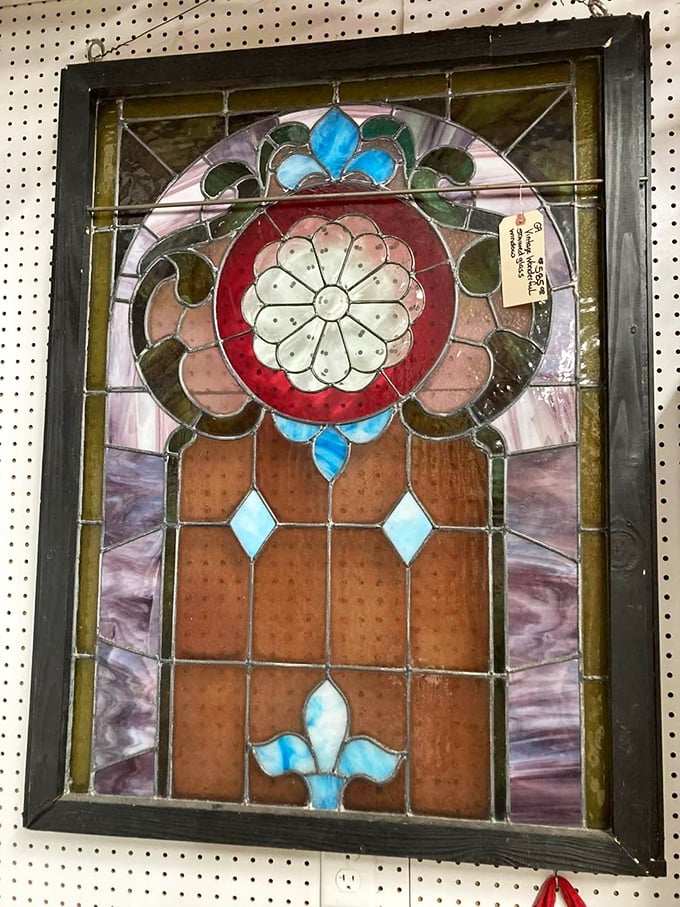 Sunlight streams through this rescued church window, casting colorful shadows that dance across the floor. Once it illuminated prayers, now it waits for a second life.
