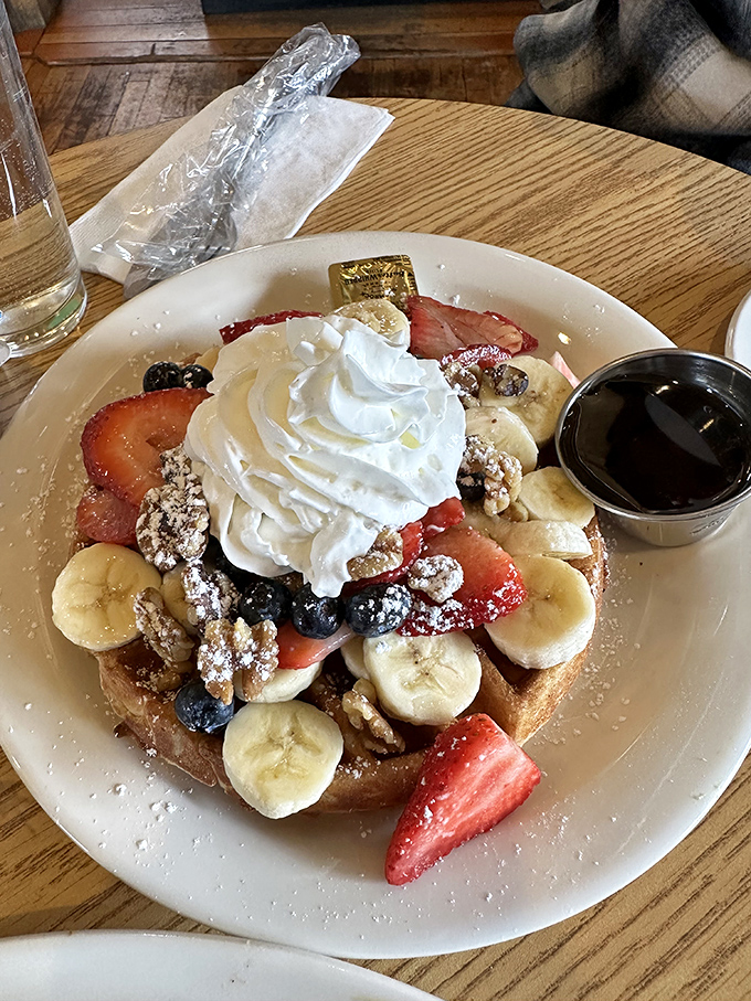 This waffle doesn't just carry toppings; it hosts a celebration of fruit, whipped cream, and nuts that would make IHOP question their life choices. 