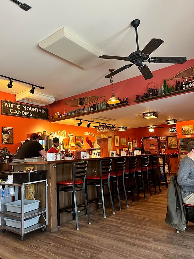 The counter where breakfast dreams come true. Orange walls warm like morning sunshine while vintage signs whisper of simpler, tastier times.
