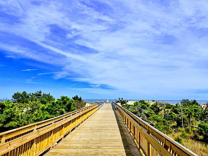 The wooden boardwalk stretches toward the horizon, inviting visitors to leave footprints in the sand while the Atlantic whispers promises of serenity.