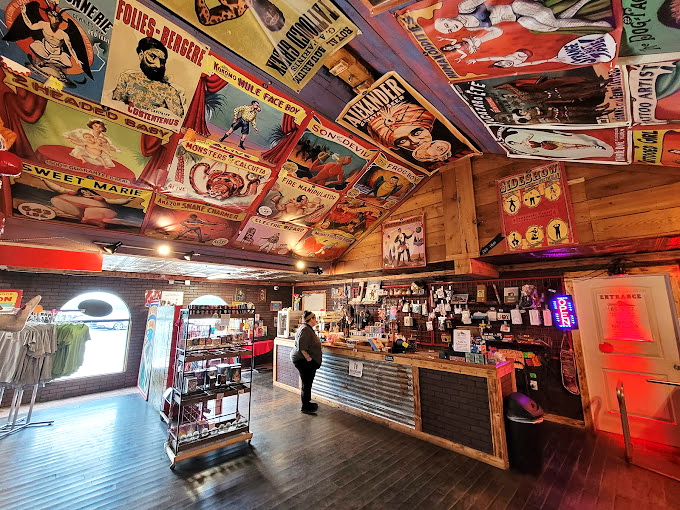 The ceiling plastered with vintage circus posters and sideshow advertisements sets a carnival-like tone. Even the lighting fixtures contribute to the delightfully over-the-top atmosphere.