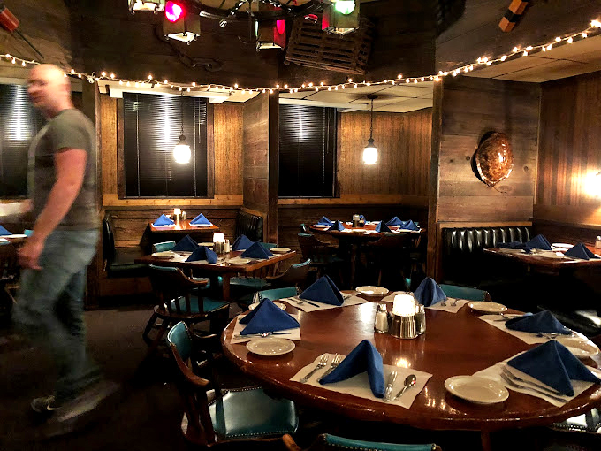 The dining room wears its nautical theme like a well-tailored captain's uniform&mdash;dignified blue napkins stand at attention on tables awaiting their seafaring feast.