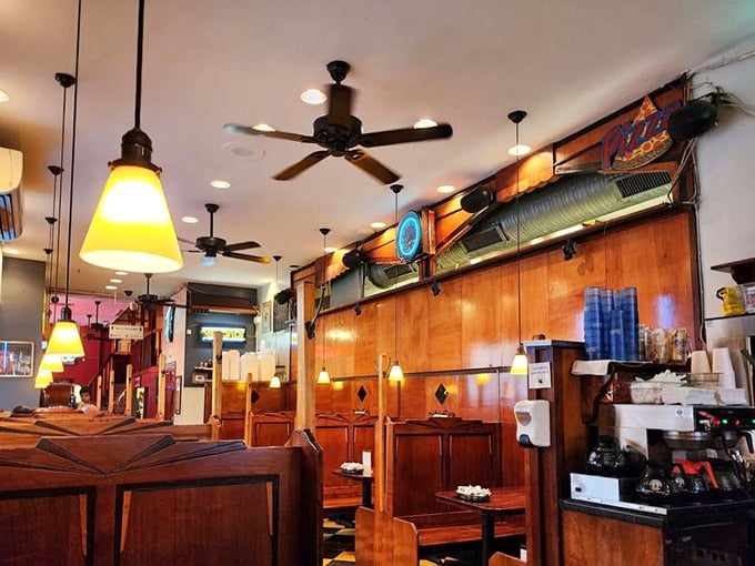 Warm pendant lighting casts a golden glow over polished wood booths. Ceiling fans spin lazily overhead, keeping time with conversations below.