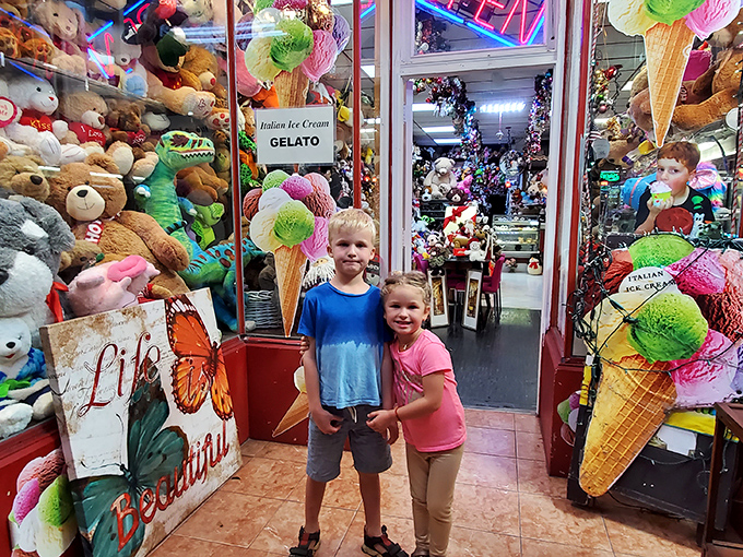 Two young explorers at the gateway to sugar paradise, flanked by ice cream cone sentinels. Their expressions say it all: mission accomplished.