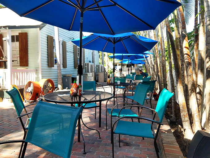 Blue umbrellas, brick pavers, and tropical breezes &ndash; the outdoor seating area practically whispers, "Stay awhile, order another round."