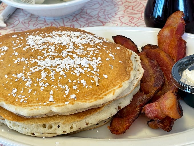 Pancakes so perfectly golden they belong in Fort Knox, with crispy bacon standing guard against anyone who might try to steal a bite.