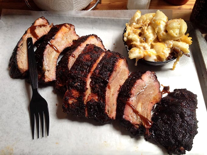 Slices of brisket with edges blackened by fire's loving touch, paired with mac and cheese that's achieved golden, bubbling perfection.