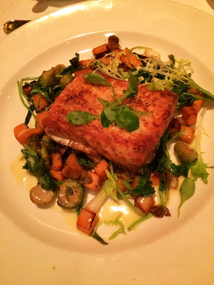 Salmon that doesn't need to swim upstream to impress, perched atop a colorful medley of vegetables like edible modern art.