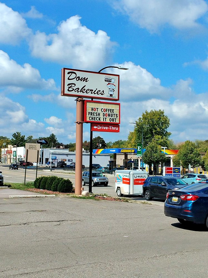 The humble storefront hides its treasures like a speakeasy for sugar enthusiasts. That "HOT DONUTS" sign is truth in advertising.