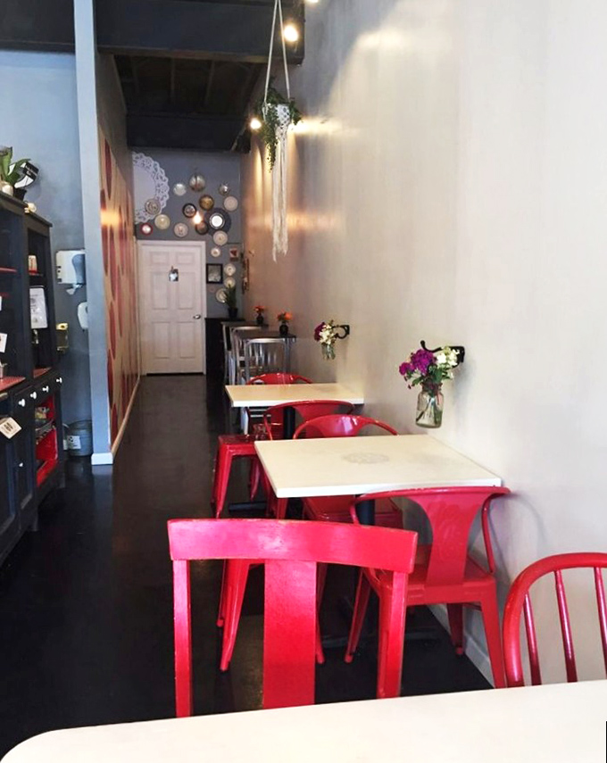 The cozy interior with bright red chairs invites you to sit and stay awhile. These tables have witnessed countless first bites and happy sighs.