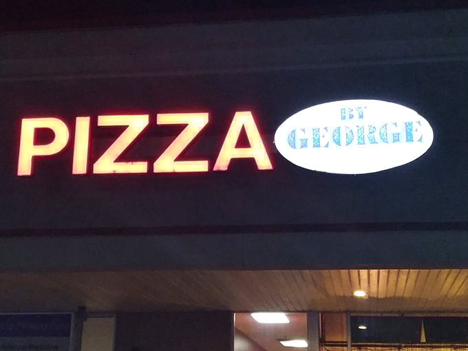 Pizza by George's glowing sign cuts through the night like a lighthouse, guiding hungry travelers to carb-loaded bliss.