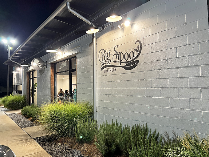 Big Spoon Creamery's white-brick exterior glows like a beacon of dairy-based hope after dark, promising sweet relief from Alabama's summer heat.