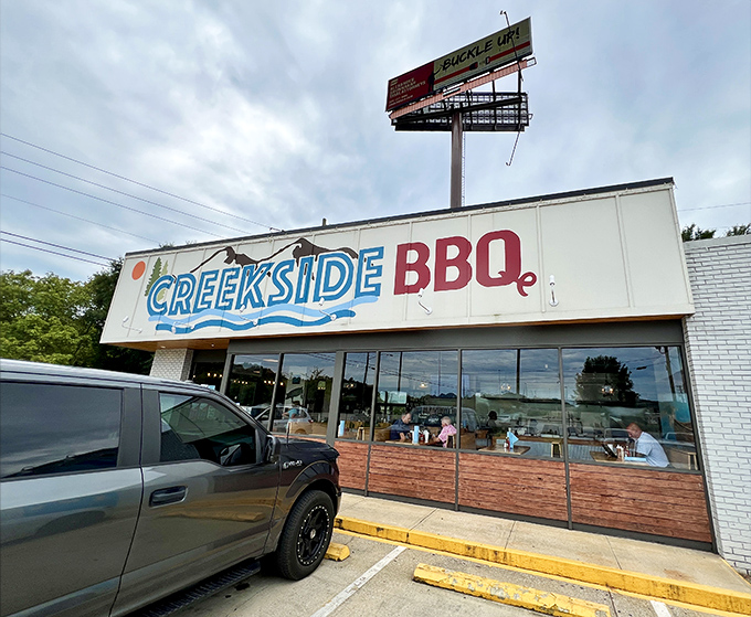 The blue and red Creekside BBQ sign beckons like a lighthouse for the hungry, promising smoky treasures inside this Pelham landmark.