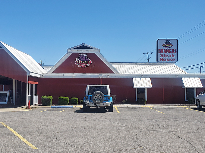The iconic red barn exterior of Brangus Steakhouse stands out against the Arkansas sky like a beacon for hungry travelers seeking serious steak satisfaction.