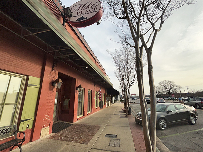The vibrant red exterior of Mike's Place, framed by blooming crepe myrtles, stands as Conway's culinary beacon for seafood lovers.