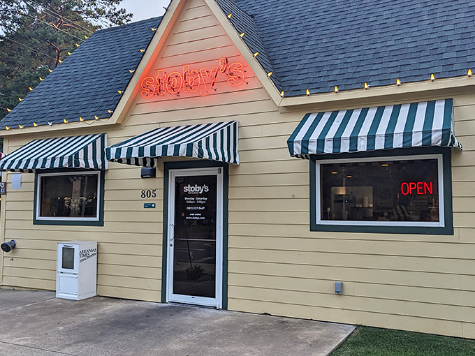 The cheerful yellow exterior of Stoby's with its iconic striped awnings stands like a beacon of comfort food promise in Conway.