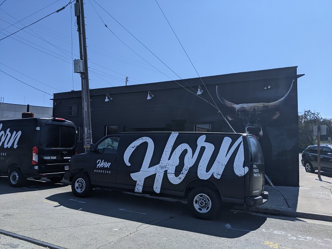 The unassuming exterior of Horn BBQ in Oakland &ndash; where that bold white lettering against dark panels is the architectural equivalent of a whisper about the best-kept secret in town.