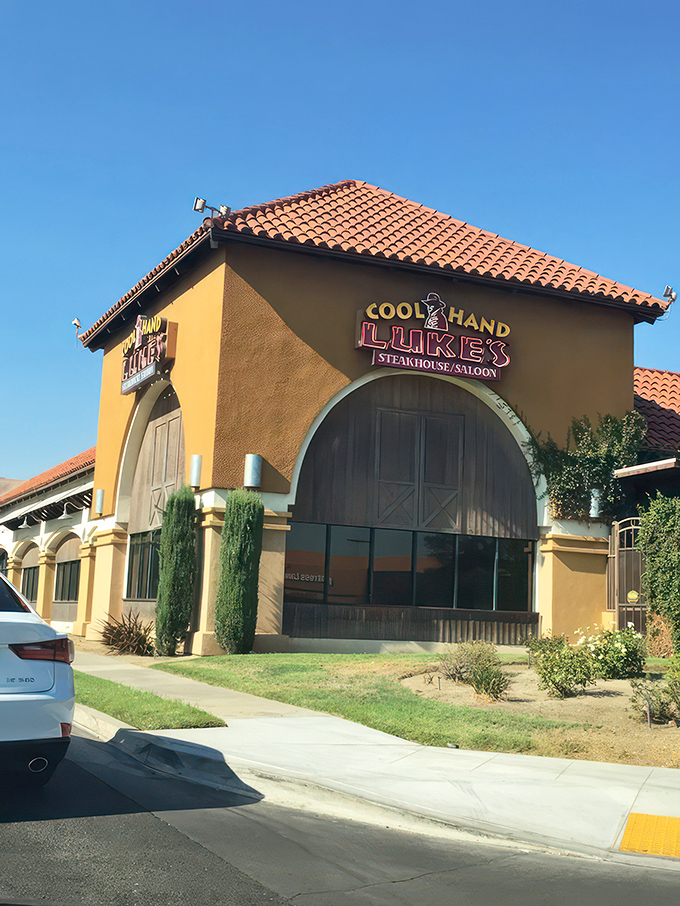 The Western-themed exterior of Cool Hand Luke's beckons with its iconic cactus sentinels and vintage wagon&mdash;like stepping onto a movie set where dinner is the star attraction.