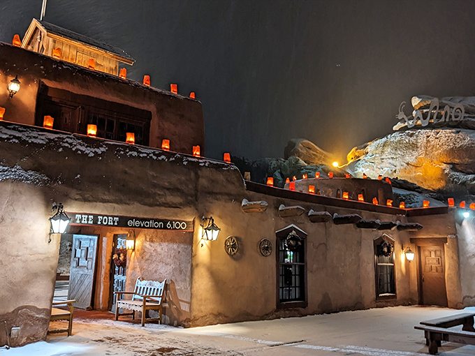 The Fort's adobe entrance glows with warmth against the night sky, luminous farolitos beckoning hungry travelers to step back in time at 6,100 feet elevation.