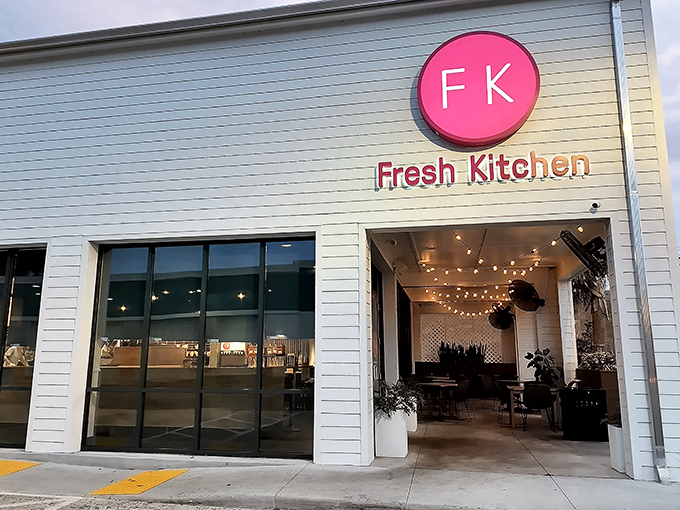 Fresh Kitchen's crisp white exterior with that eye-catching magenta logo stands out like a culinary beacon among Lakeland's palm trees.
