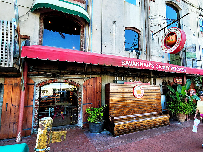 The iconic red awning of Savannah's Candy Kitchen beckons like a sweet siren call on River Street. Rustic wooden doors and lush planters create the perfect entrance to sugar paradise.