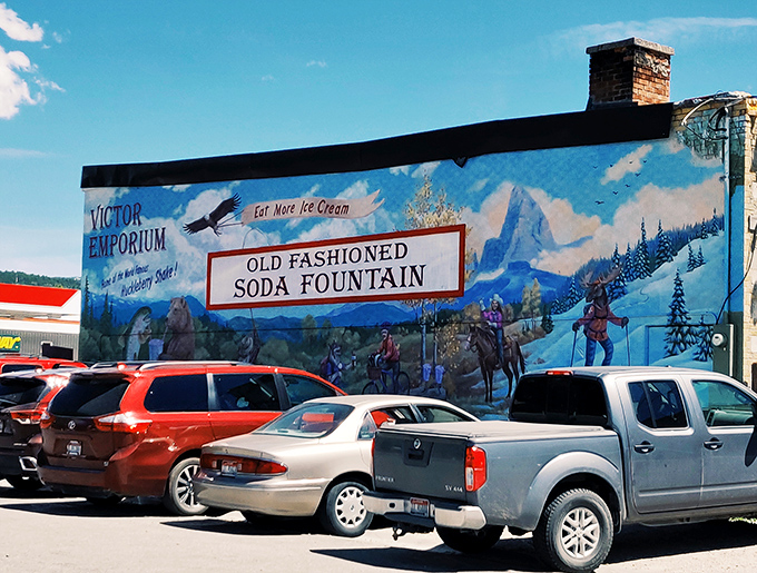 The mural-adorned exterior of Victor Emporium stands like a portal to simpler times, beckoning travelers with promises of icy purple perfection beneath Teton skies.
