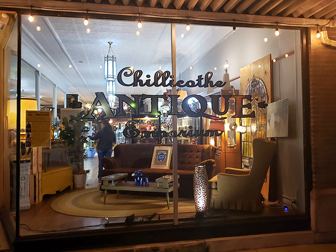 The storefront beckons like a time portal, with mid-century furniture artfully arranged behind glass and that glowing "Chillicothe ANTIQUE" sign promising adventures in nostalgia.