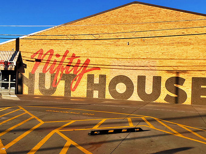 The brick facade of Nifty Nut House stands like a temple to temptation, its bold red script promising sweet adventures within.