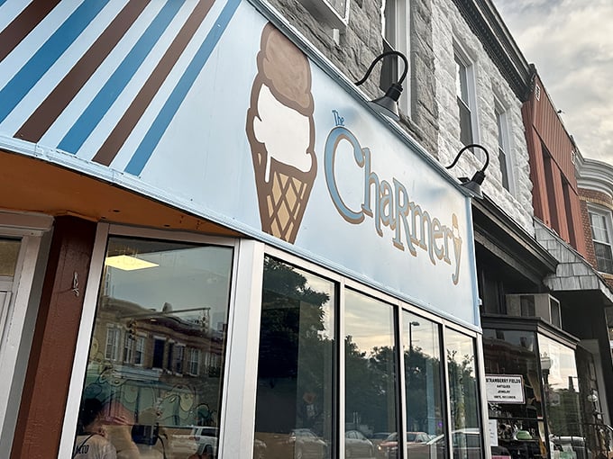 The corner shop that launched a thousand cravings. The Charmery's blue-striped awning and iconic ice cream cone logo beckon from Hampden's bustling Avenue.
