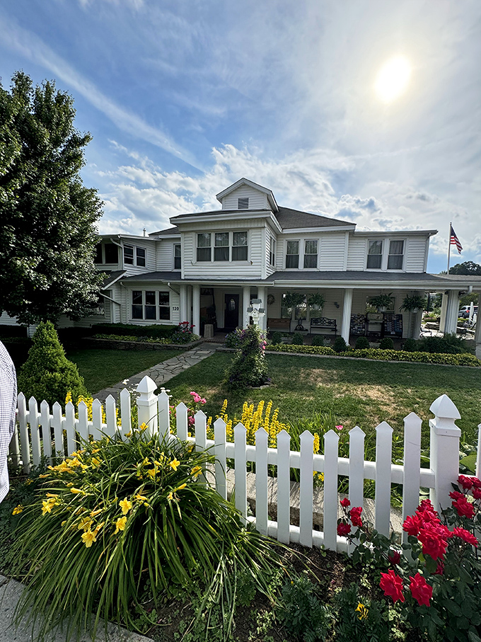 The white clapboard building with its picket fence and American flag stands as a testament to timeless Appalachian hospitality in downtown Boone.