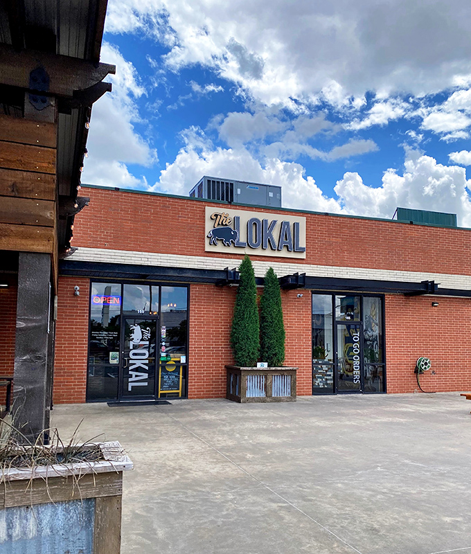 The unassuming brick exterior of The Lokal belies the culinary treasures within. Those two cypress trees stand like sentinels guarding Oklahoma's best-kept secret.