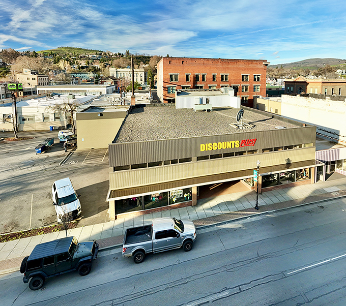 The bright yellow and red Discounts Plus sign beckons like a lighthouse for bargain hunters navigating the sea of retail prices.