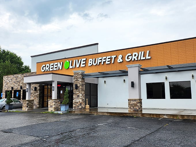 The golden-orange facade of Green Olive Buffet stands like a beacon to hungry travelers. Stone accents and modern signage promise culinary adventures within.
