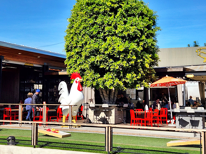 The giant rooster statue stands guard like a poultry bouncer, welcoming hungry pilgrims to this open-air temple of fried chicken perfection.