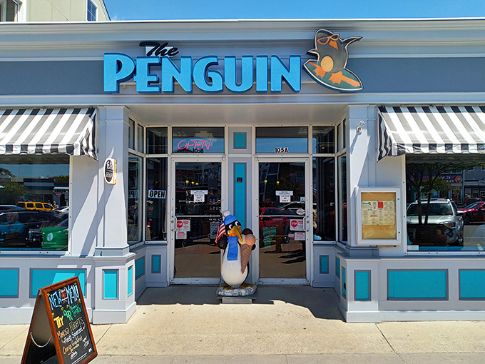The Penguin's cheerful blue sign and tuxedoed mascot stand ready to welcome hungry beachgoers&mdash;like a breakfast ambassador promising morning delights just steps from the sand.
