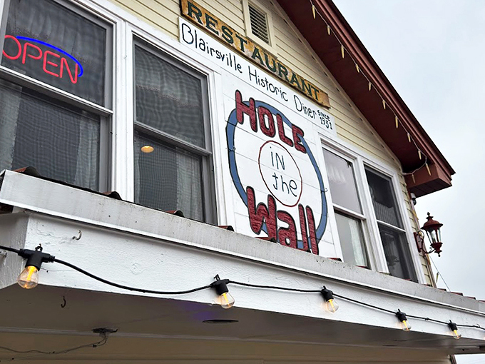 The iconic facade of Hole in the Wall beckons hungry travelers with its charming hand-painted sign and string lights&mdash;a North Georgia breakfast beacon worth the drive.