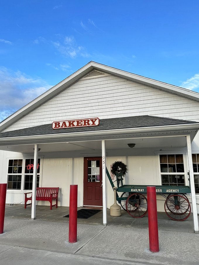 The quintessential country bakery facade&mdash;white clapboard, red accents, and a wooden wagon that silently promises carbs worth every mile of your journey.