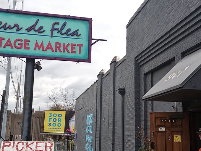The turquoise sign beckons like a vintage siren song, promising treasures behind those brick walls that your modern big-box stores couldn't dream of housing.