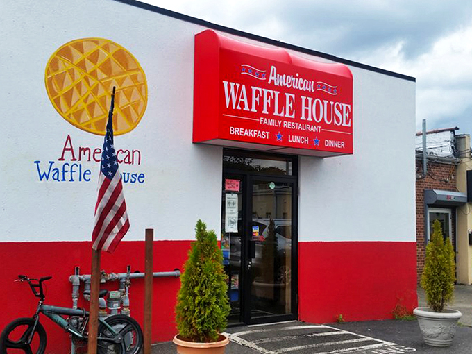 The bright red exterior of American Waffle House stands like a beacon of breakfast hope on Merrick Road. Resistance is futile.