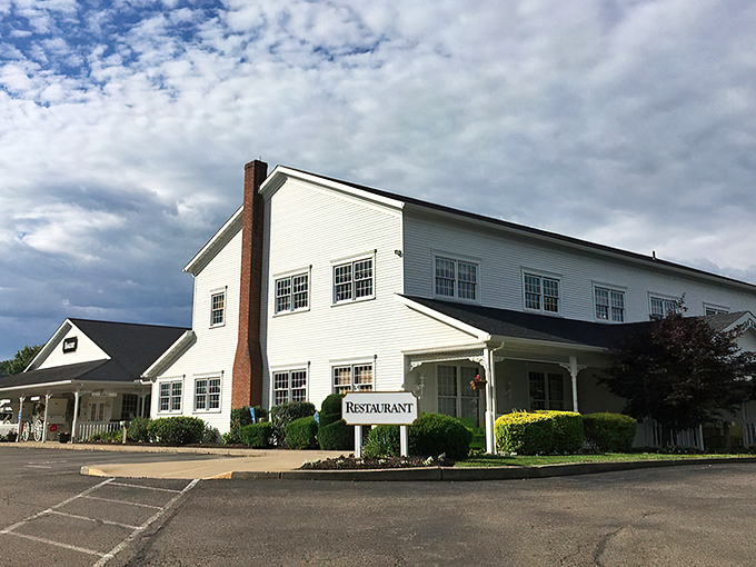 The classic white clapboard exterior of Amish Door Restaurant stands like a beacon of comfort food promise against Ohio's big sky.