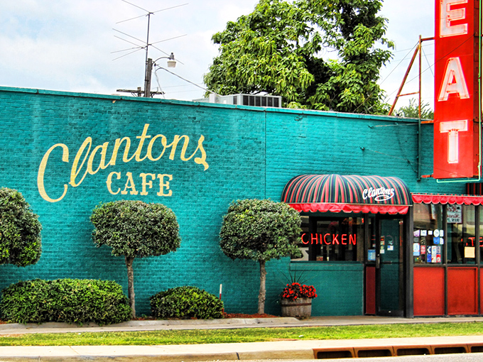 The vibrant turquoise and red exterior of Clanton's Café stands as a colorful beacon on Route 66, promising comfort food treasures within those striped awnings.